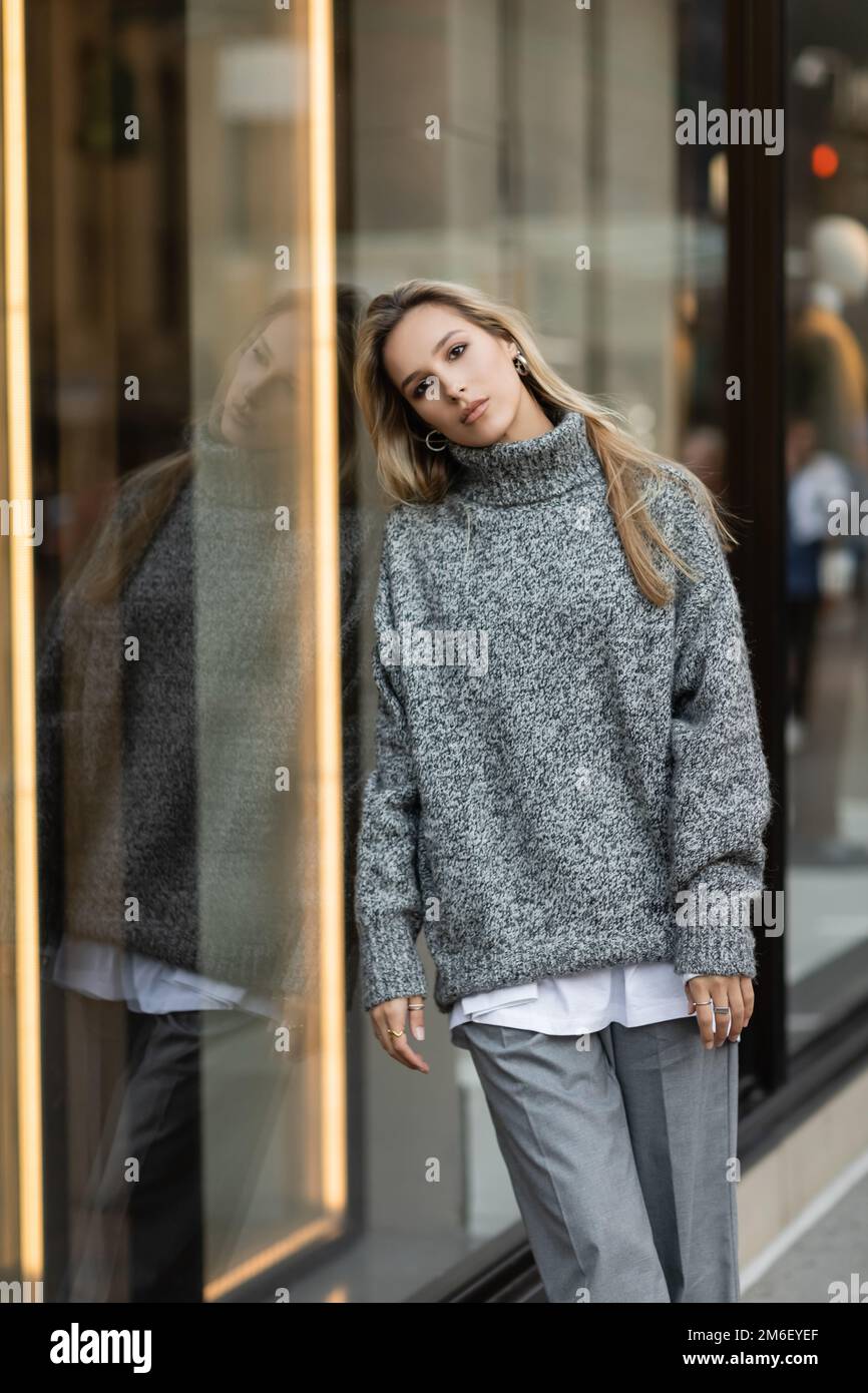 young woman in grey outfit leaning on window display in New York,stock ...