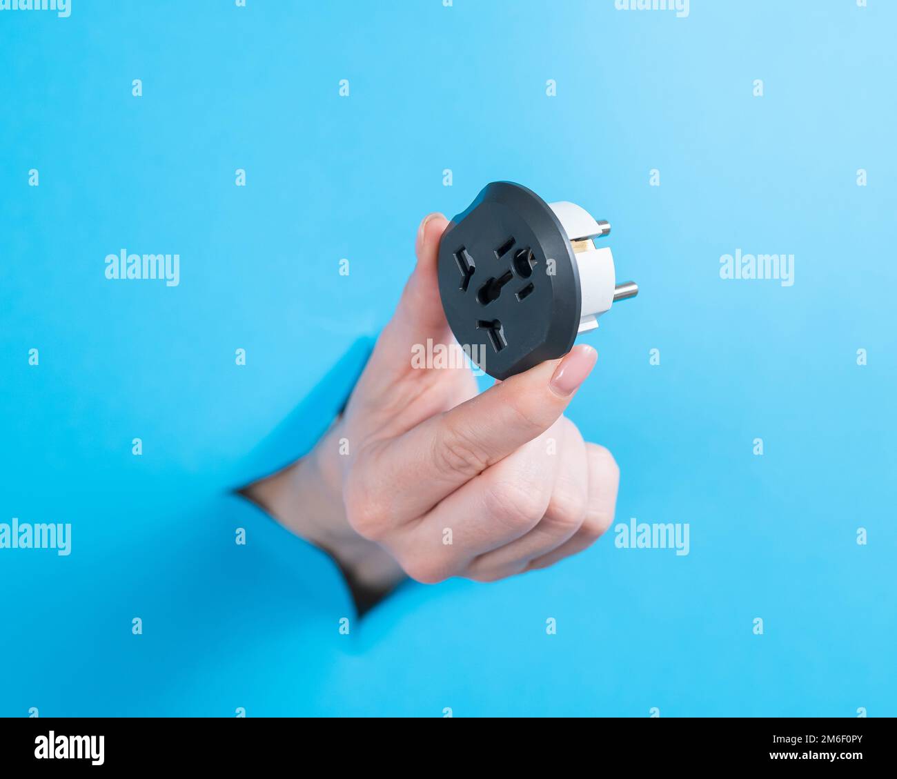 A woman is holding an outlet adapter. A woman's hand sticks out through ...