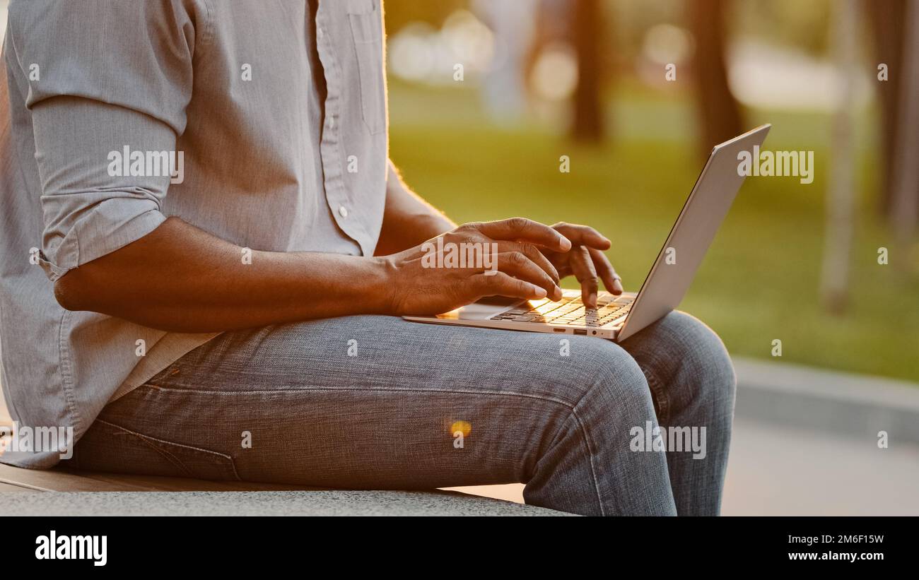 Closeup male hands texting working on wireless laptop device in city ...
