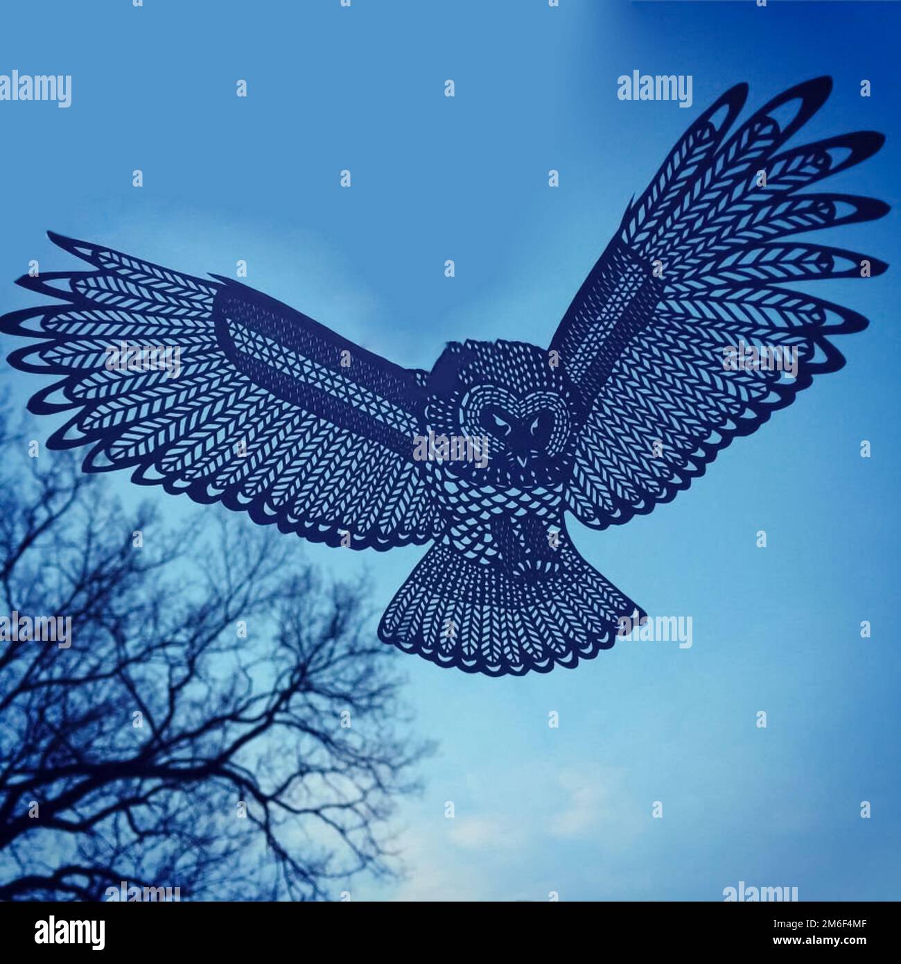 Paper-cut owl on a background of the sky. Animal figurines carved from ...