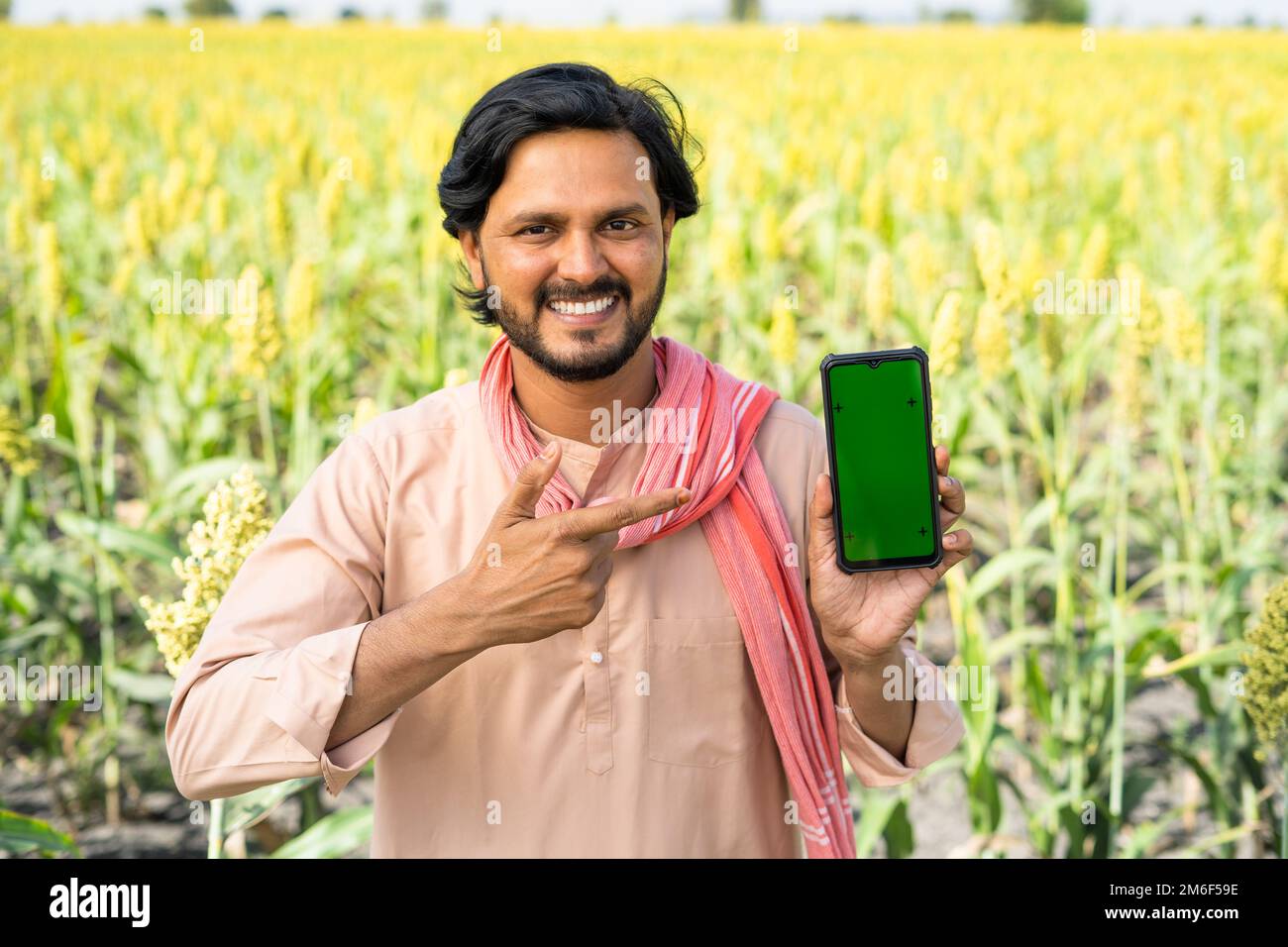 smiling farmer showing green screen mobile phone by pointing finger by ...