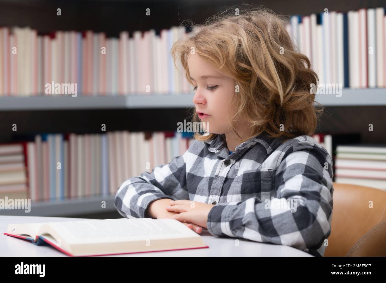 Childhood and education concept. Child reading a book in a school ...