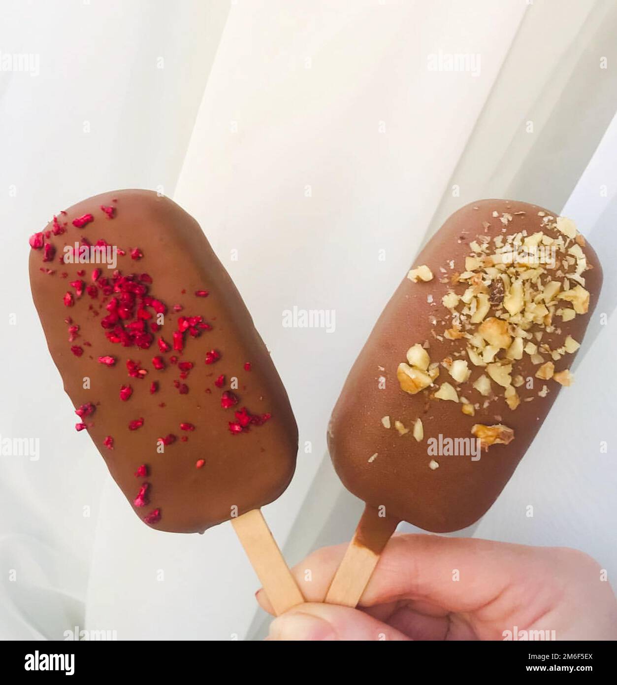 Two Eskimo ice creams on wooden stick in hand Stock Photo - Alamy