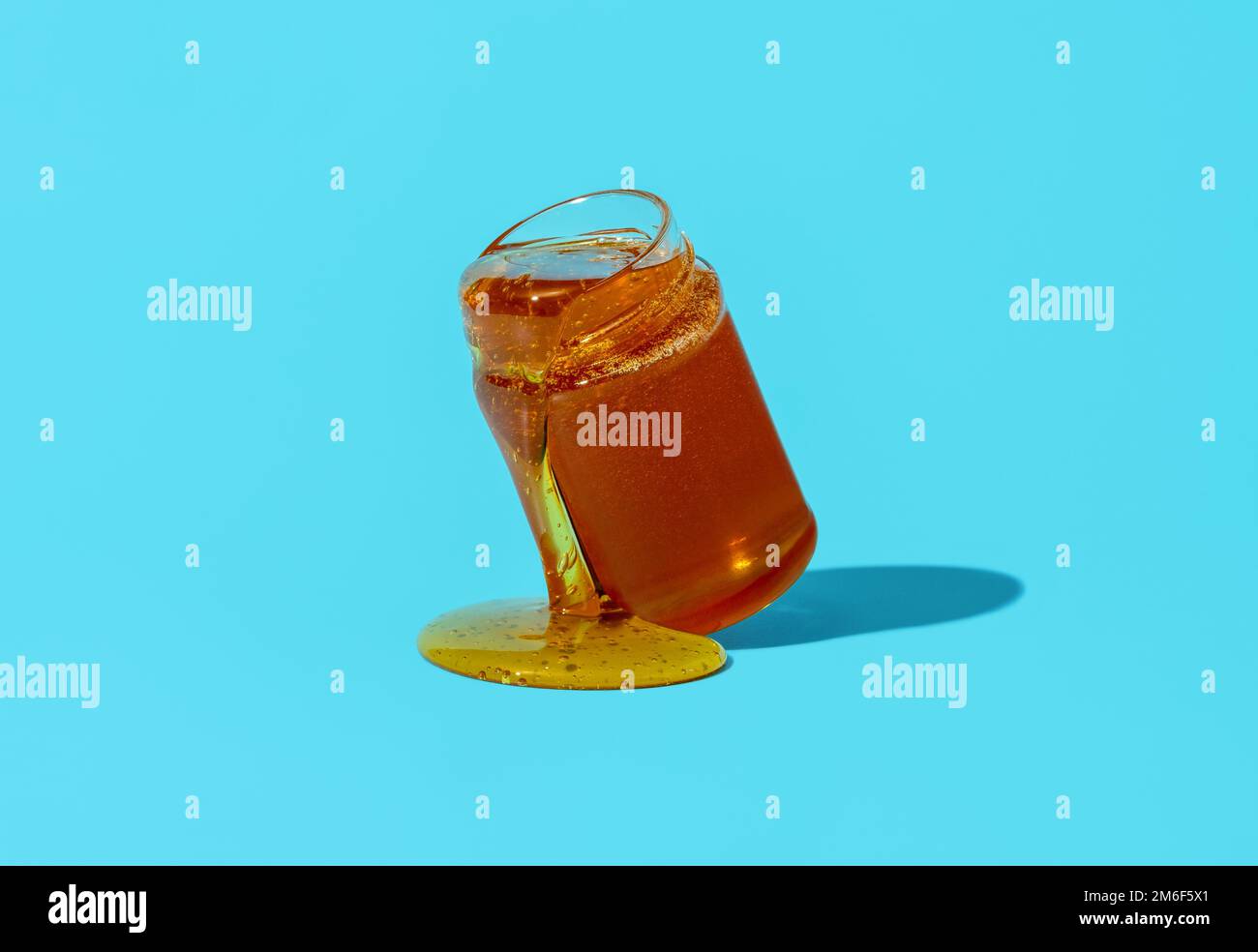 Jar with honey minimalist on a blue table. Dripping honey from a glass ...