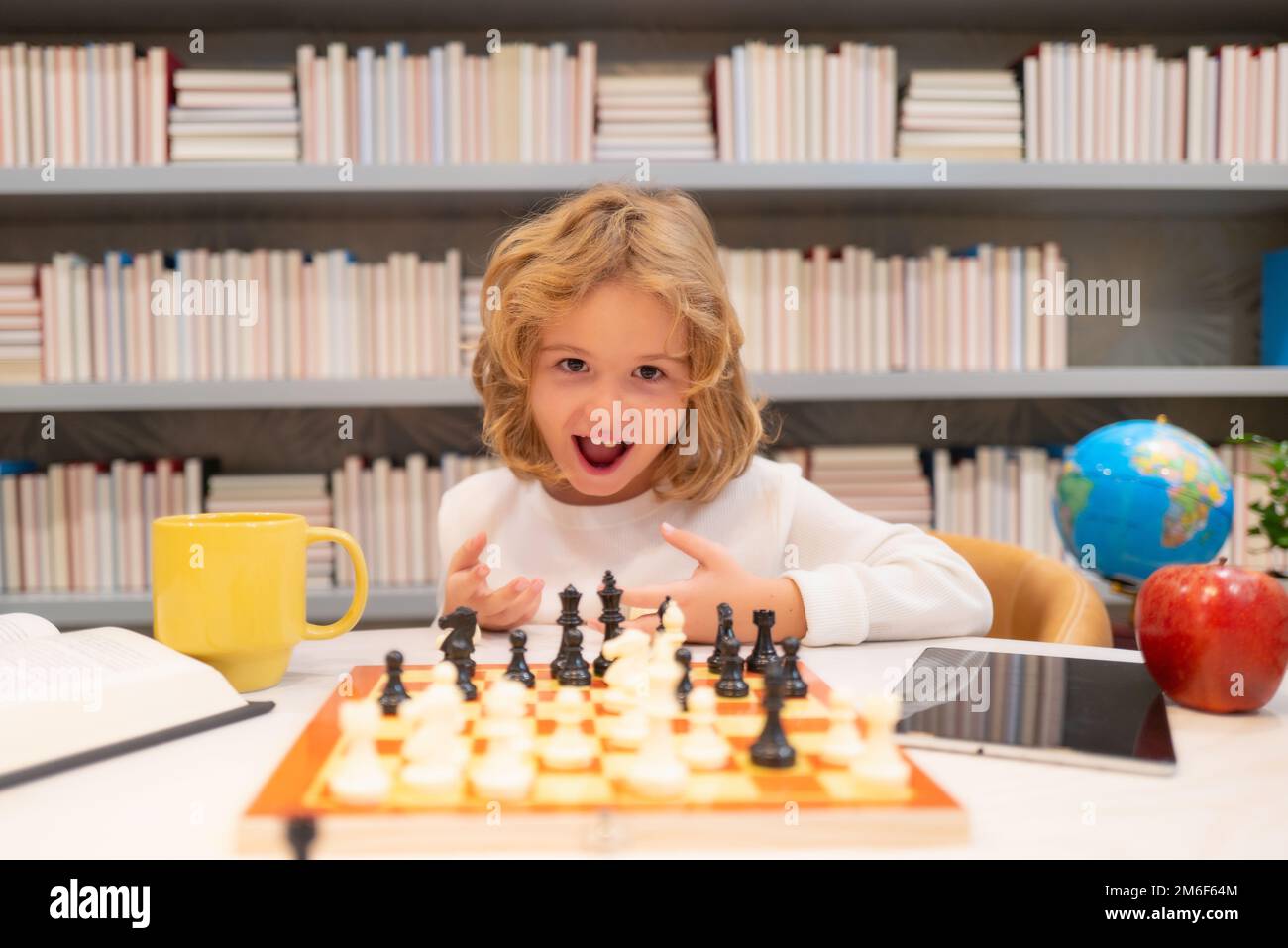 Little child play chess in classroom. Kid playing board game. Thinking ...