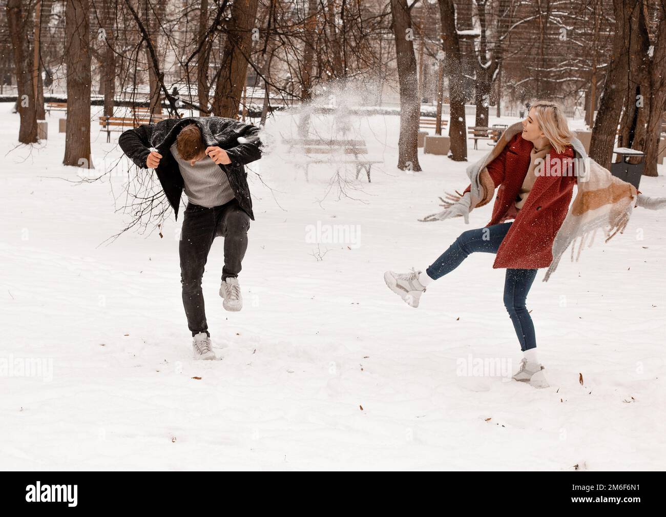 Couple playing with snow and girlfriend throwing a ball in winter holidays. Happy young ...