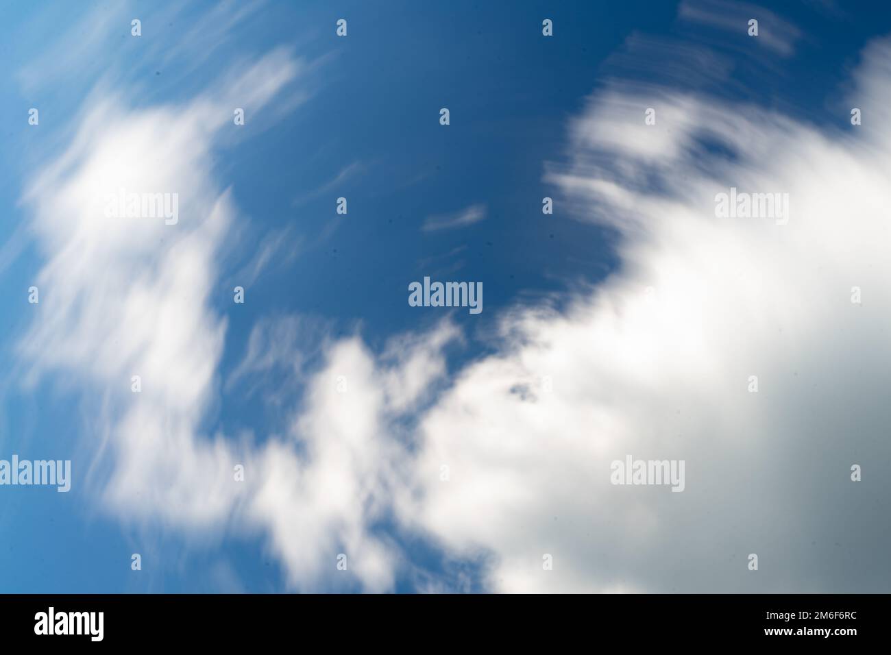 Clouds in front of blue sky with round motion blur Stock Photo - Alamy