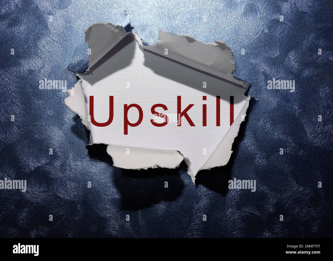 Upskill text revealed in ripped blue paper background Stock Photo - Alamy