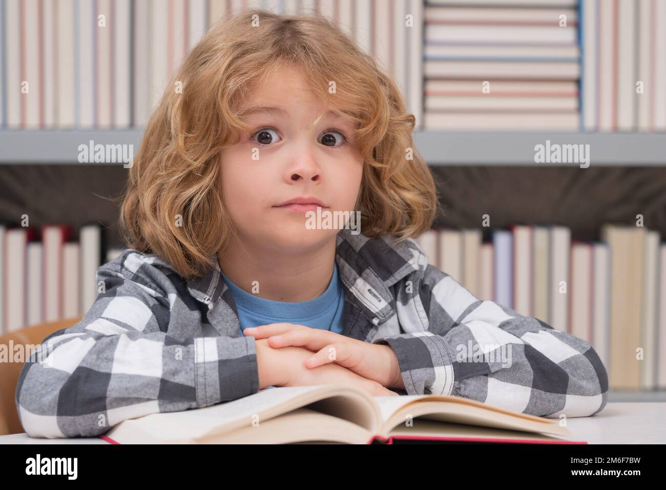 Cute school kid studying in school library. Portrait of child reading ...