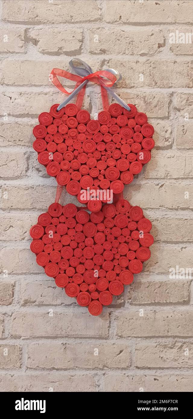 Red hearts hang on brick wall. Textured symbol of love. Two handmade ...