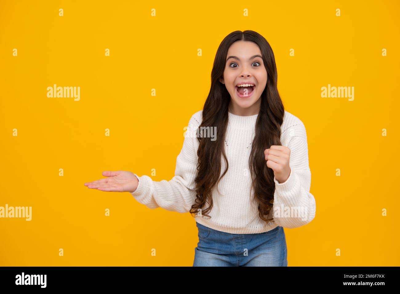 Positive teenager child points aside with cheerful expression, shows ...