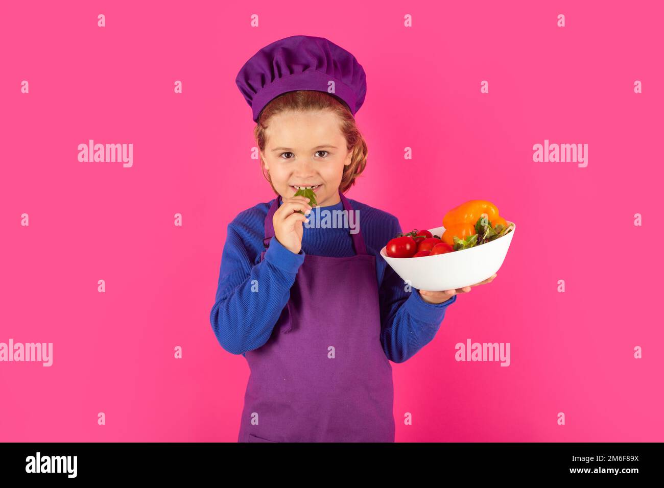 Child cook hold plate with vegetable. Chef kid boy making healthy food ...