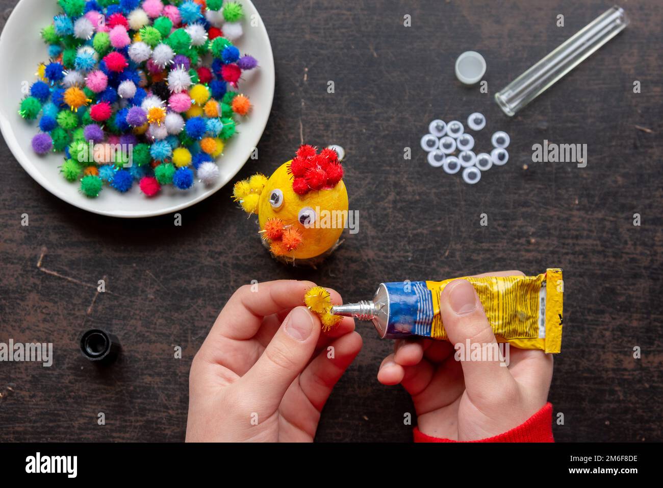 Children's hands glue the wing to the chicken figure with glue from a ...