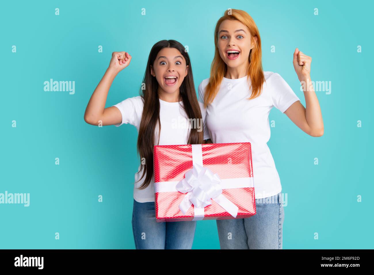Mother and daughter with present gift. Teenager girl giving gift box to her mother on blue ...