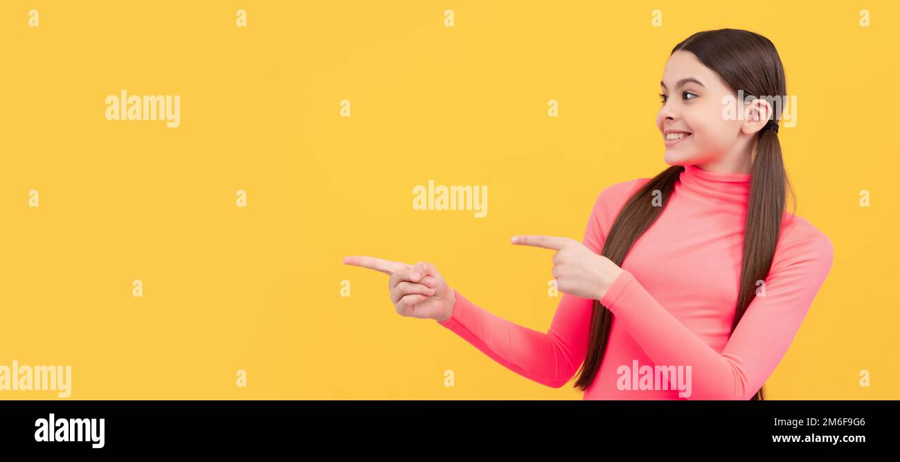 cheerful kid pointing finger on copy space. pretty teen girl ...