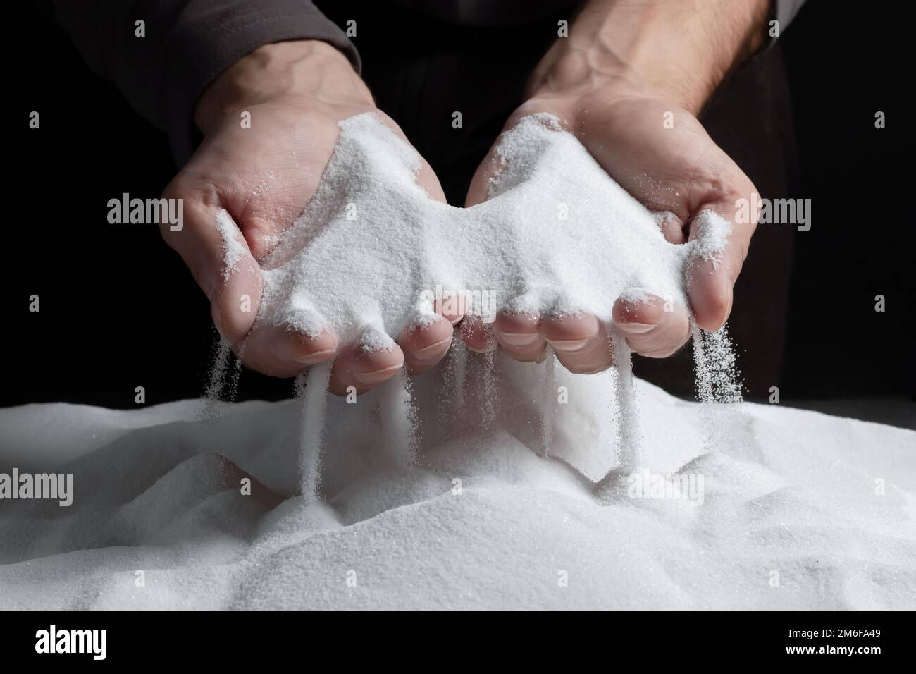 Men's hands keep sand in their palms and spilling grains of sand ...