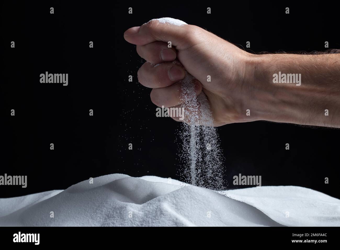 Man with handful of white dry sand in her hands, spilling sand through ...