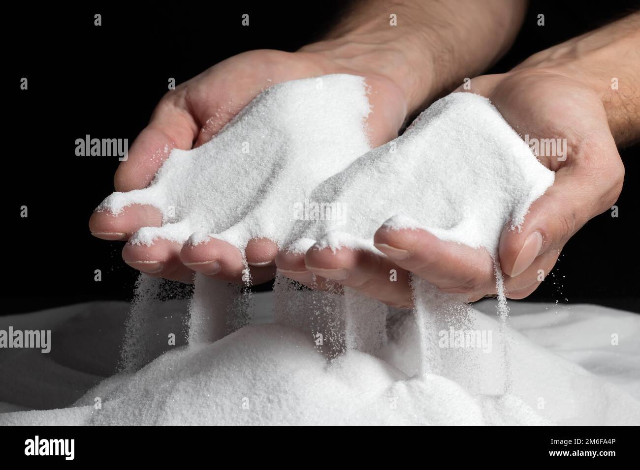 Men's hands keep sand in their palms and spilling grains of sand ...