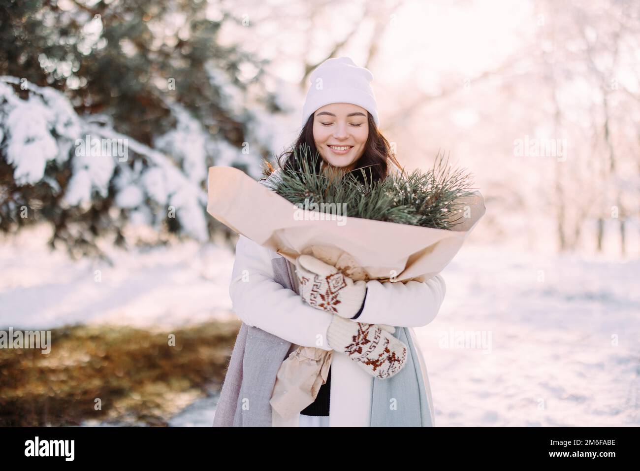 Happy young smiling woman walks in forest among snow covered trees in ...