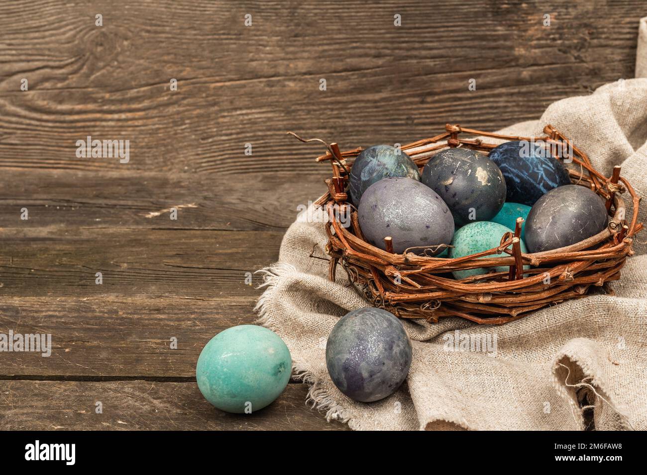 Easter eggs in wicker basket and blooming cherry on old wooden ...