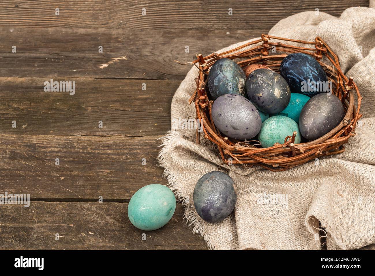 Easter eggs in wicker basket and blooming cherry on old wooden ...