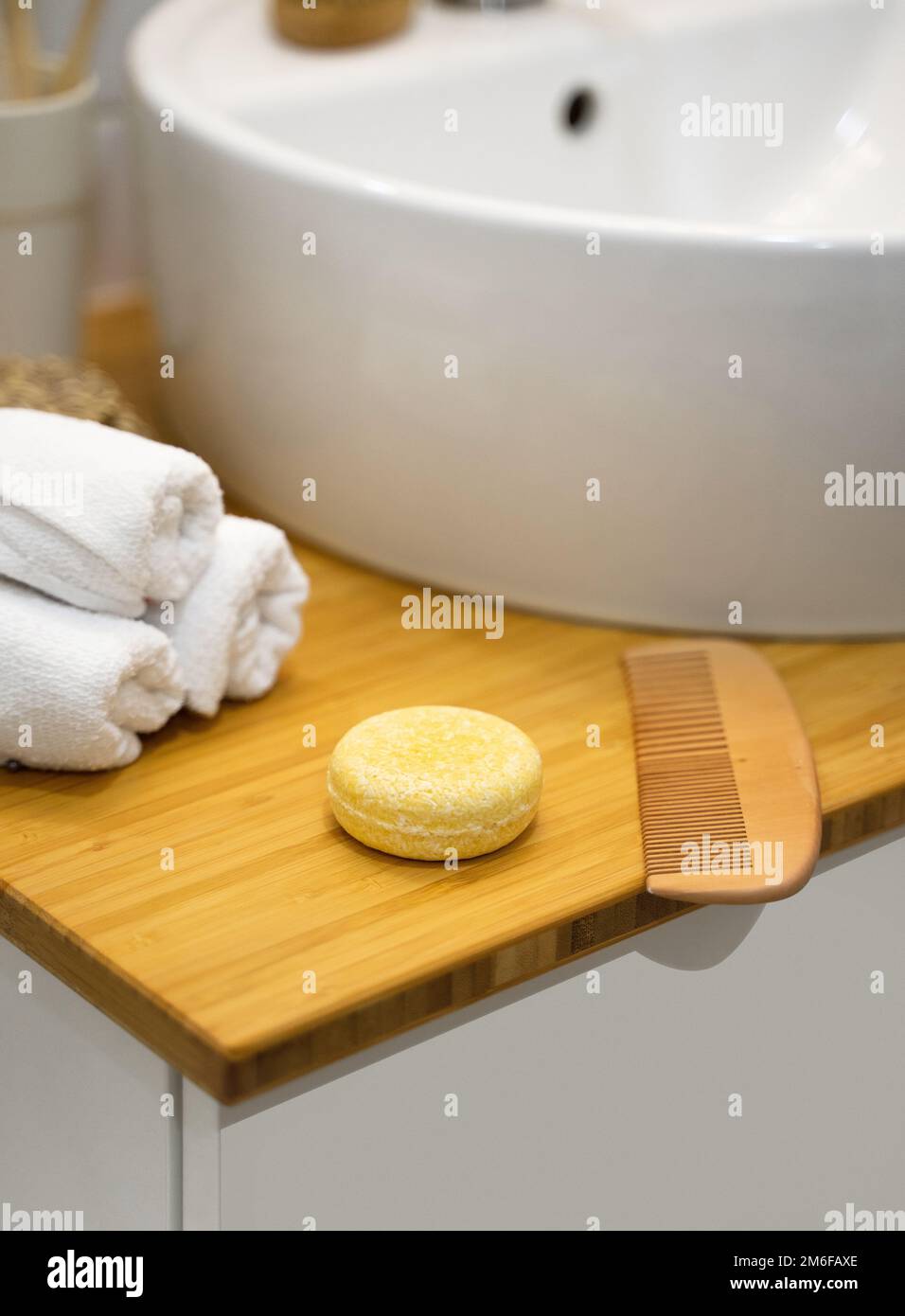 Sustainable solid shampoo bar, towels ana wooden comb on a bamboo table ...