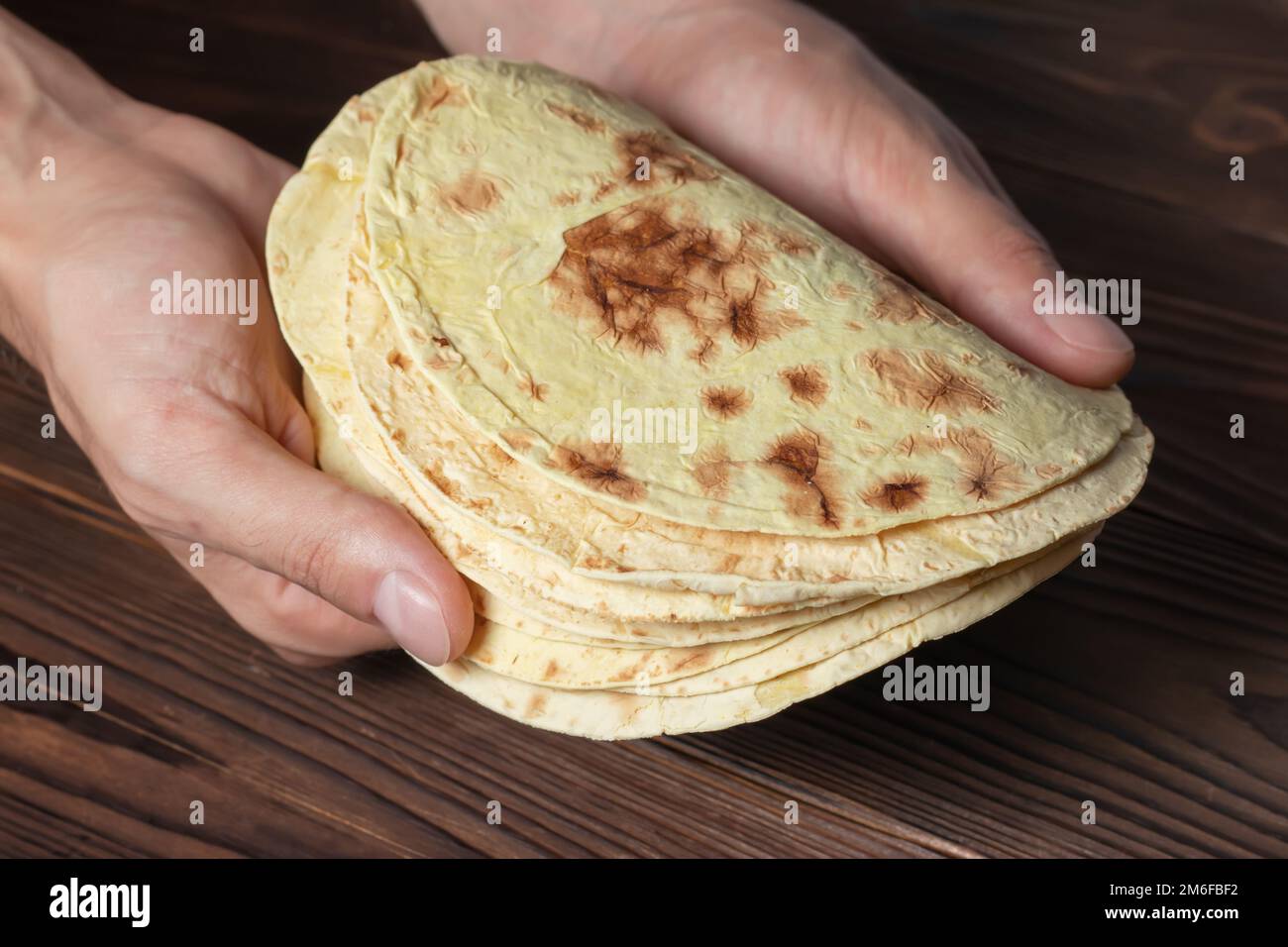 Taco lavash. Tortilla grill bread in hand wooden background Stock Photo ...