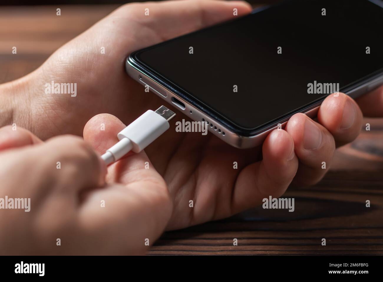 Charging a smartphone via a USB cable and a power supply. A black ...