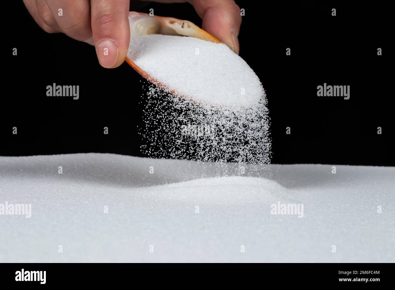 sand pouring out of sea shells on black background Stock Photo - Alamy