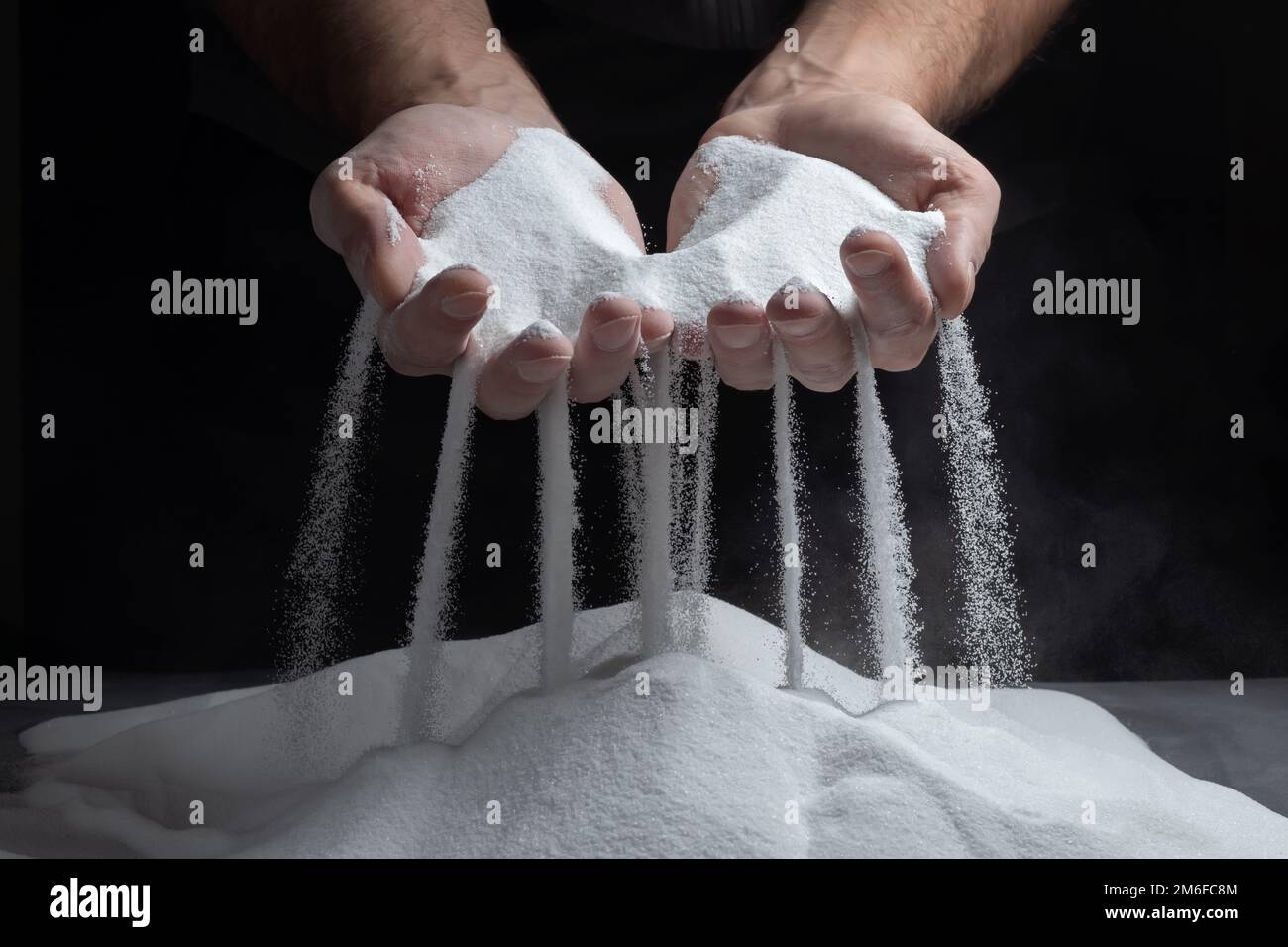Men's hands keep sand in their palms and spilling grains of sand ...