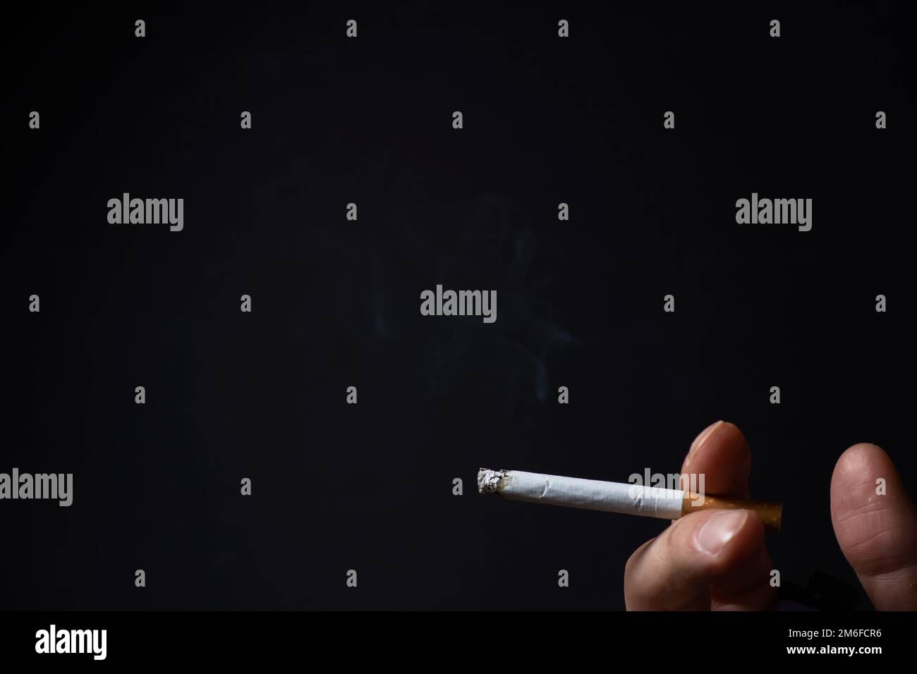 Hand with burning cigarette and smoke on black background Stock Photo ...