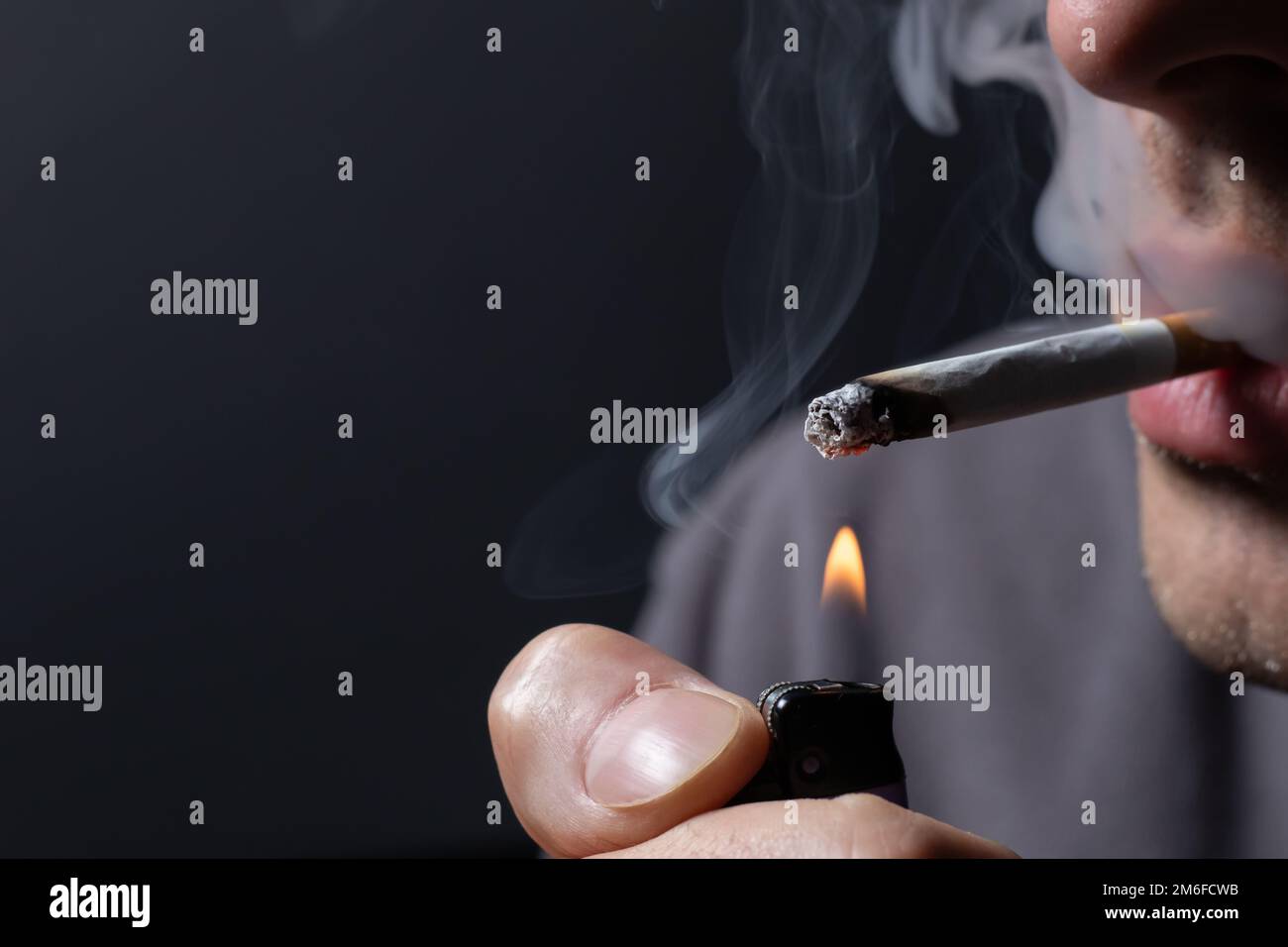 Man smoking a cigarette on black background. close up Stock Photo - Alamy