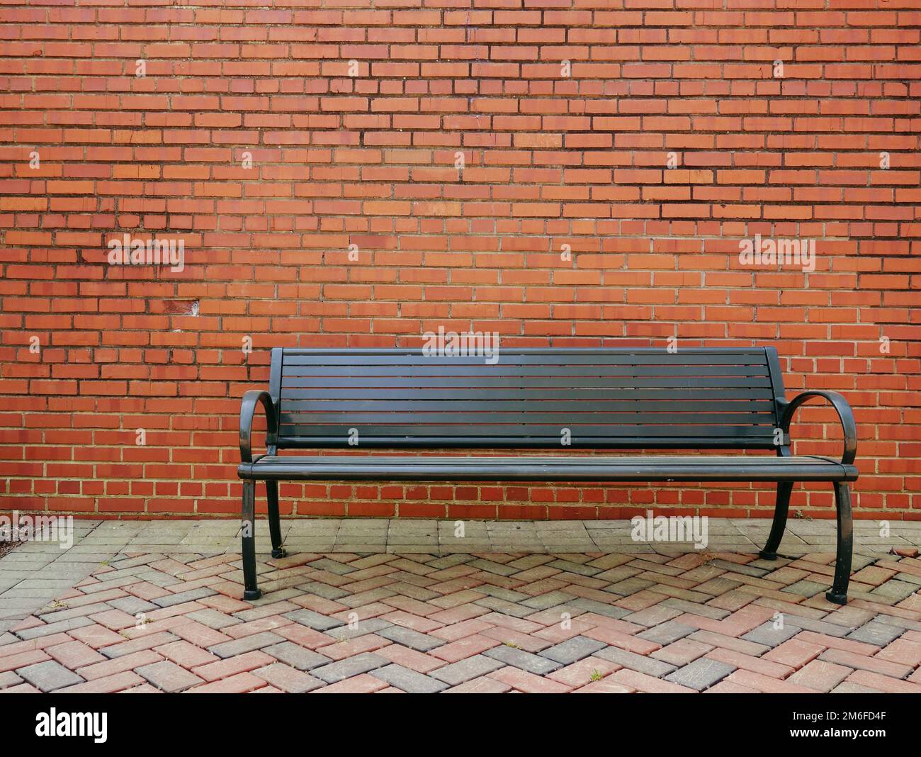 An empty park bench in front of a blank brick wall Stock Photo - Alamy