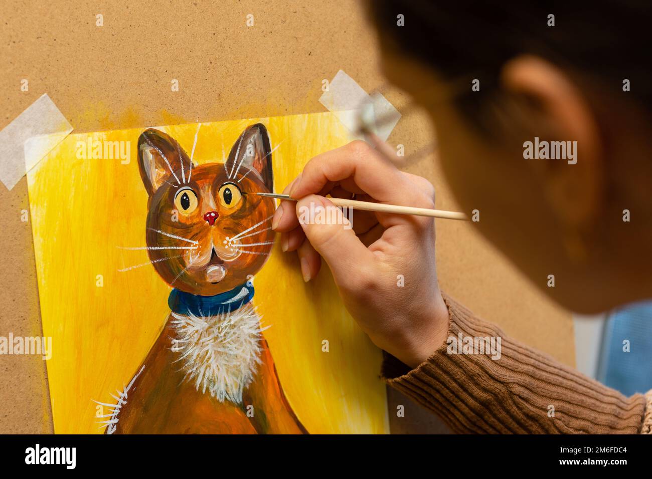 The artist draws with acrylic paints a drawing of a cat on an easel ...