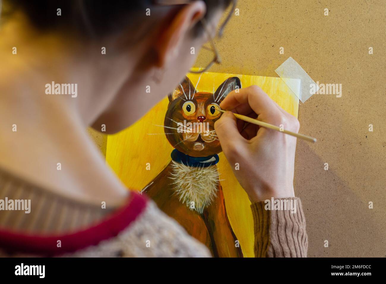 The artist paints a drawing of a cat on an easel with acrylic paints, a ...