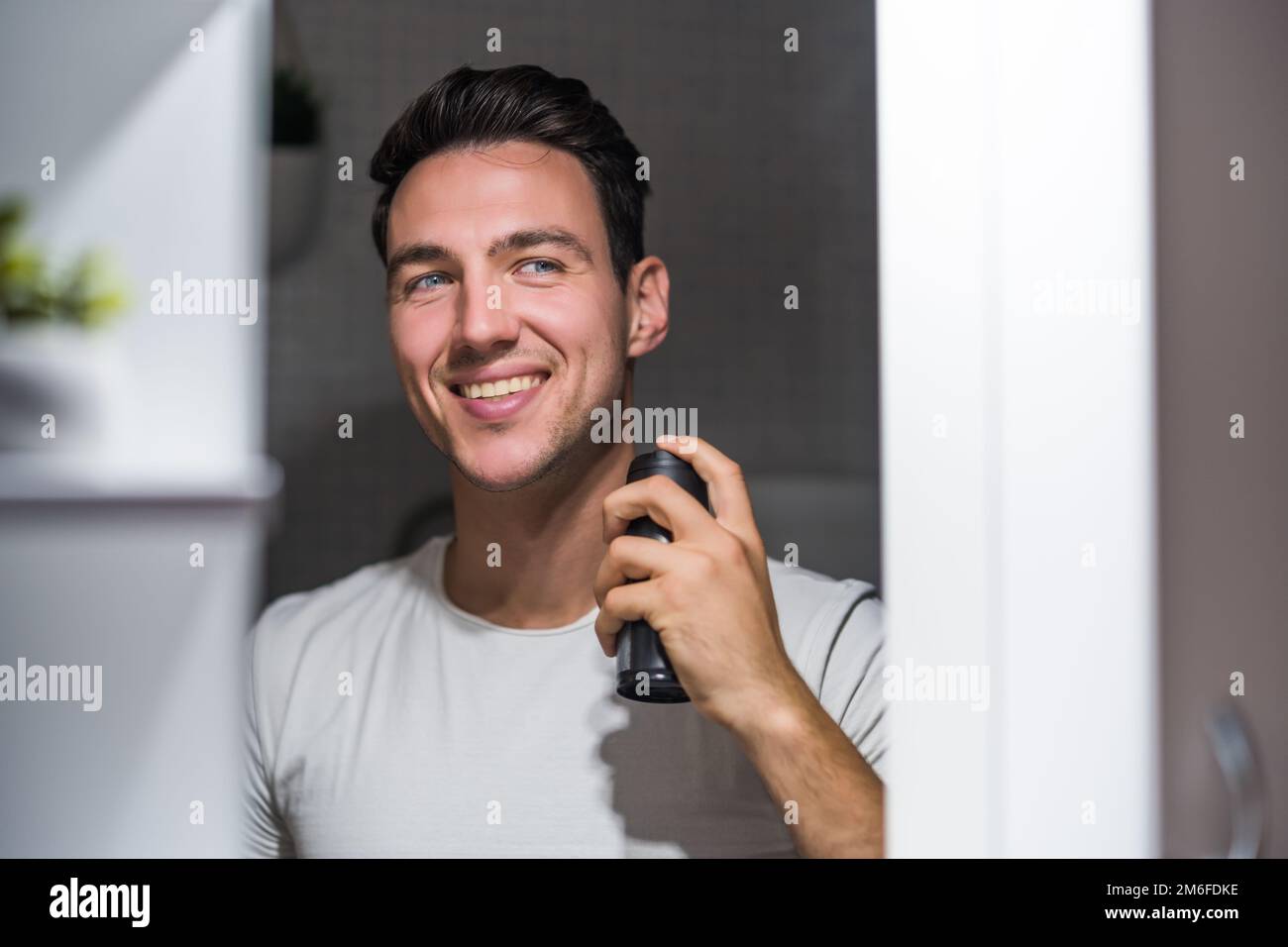 Man using deodorant while looking himself in the mirror Stock Photo - Alamy