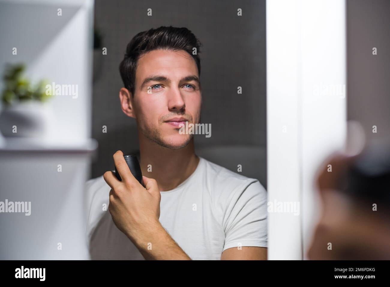 Man using deodorant while looking himself in the mirror Stock Photo - Alamy