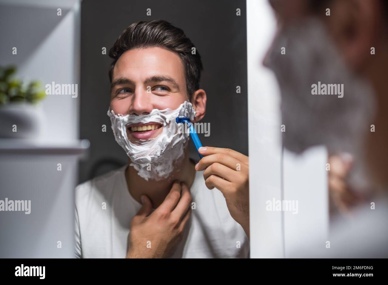 Man shaving beard while looking himself in the mirror Stock Photo - Alamy