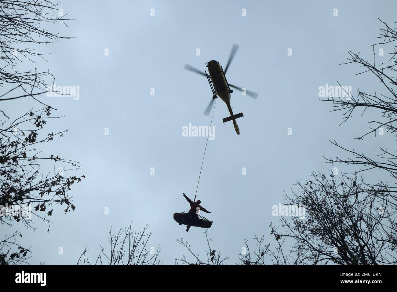 Emergency service paramedic with patient suspended by rope under ...