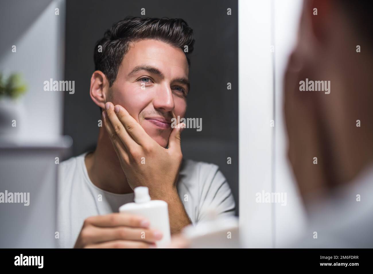 Man is applying aftershave while looking himself in the mirror Stock ...