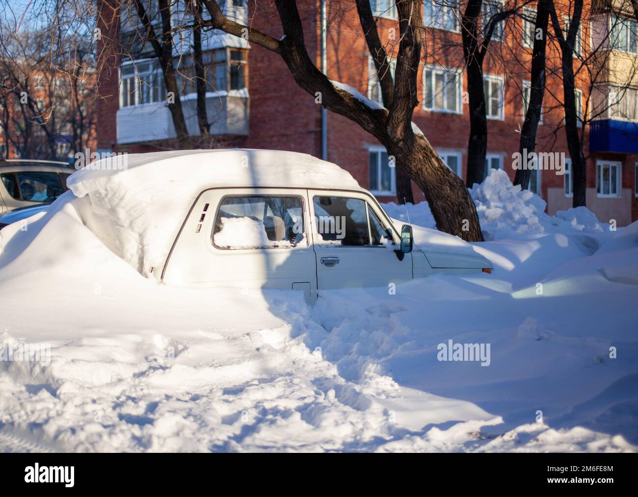 A passenger car in winter was covered with snow after a snow storm ...