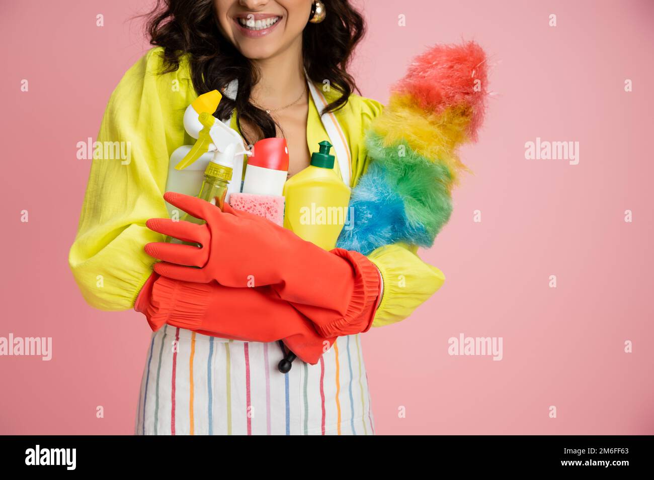 cropped view of smiling housewife in red rubber gloves holding plenty ...