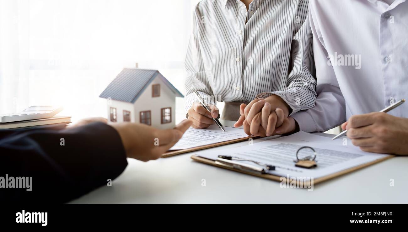 Real estate agent with couple closing a deal and signing a contract ...