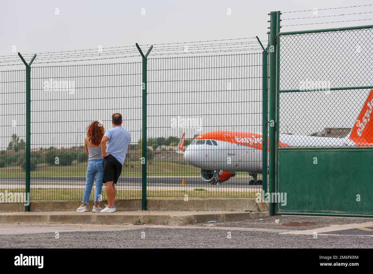 A Man and Woman at Lisbon Airport watching the EasyJet airline plane ...