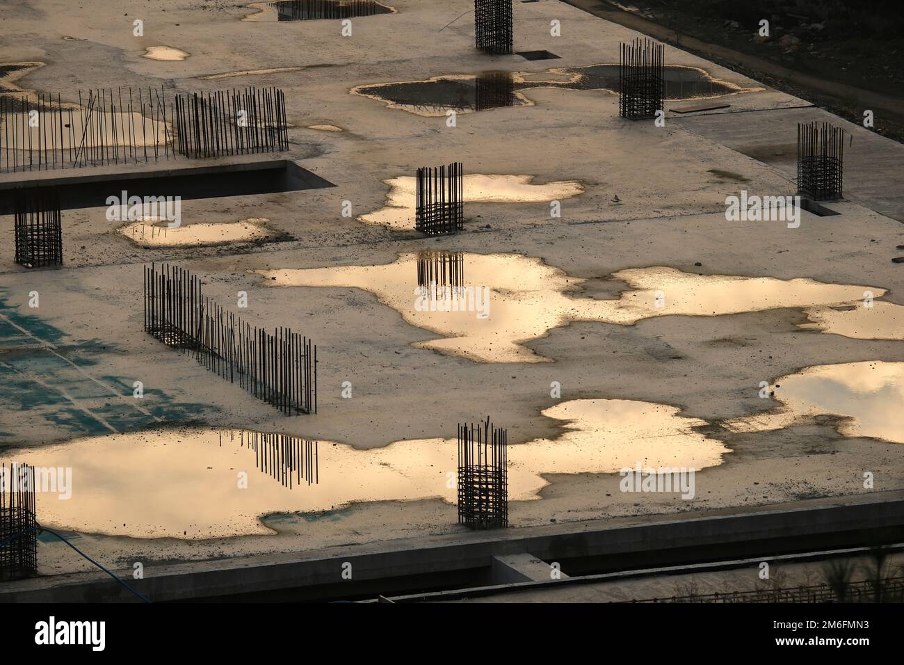 A stopped construction and rusty bars and puddles with reflections ...