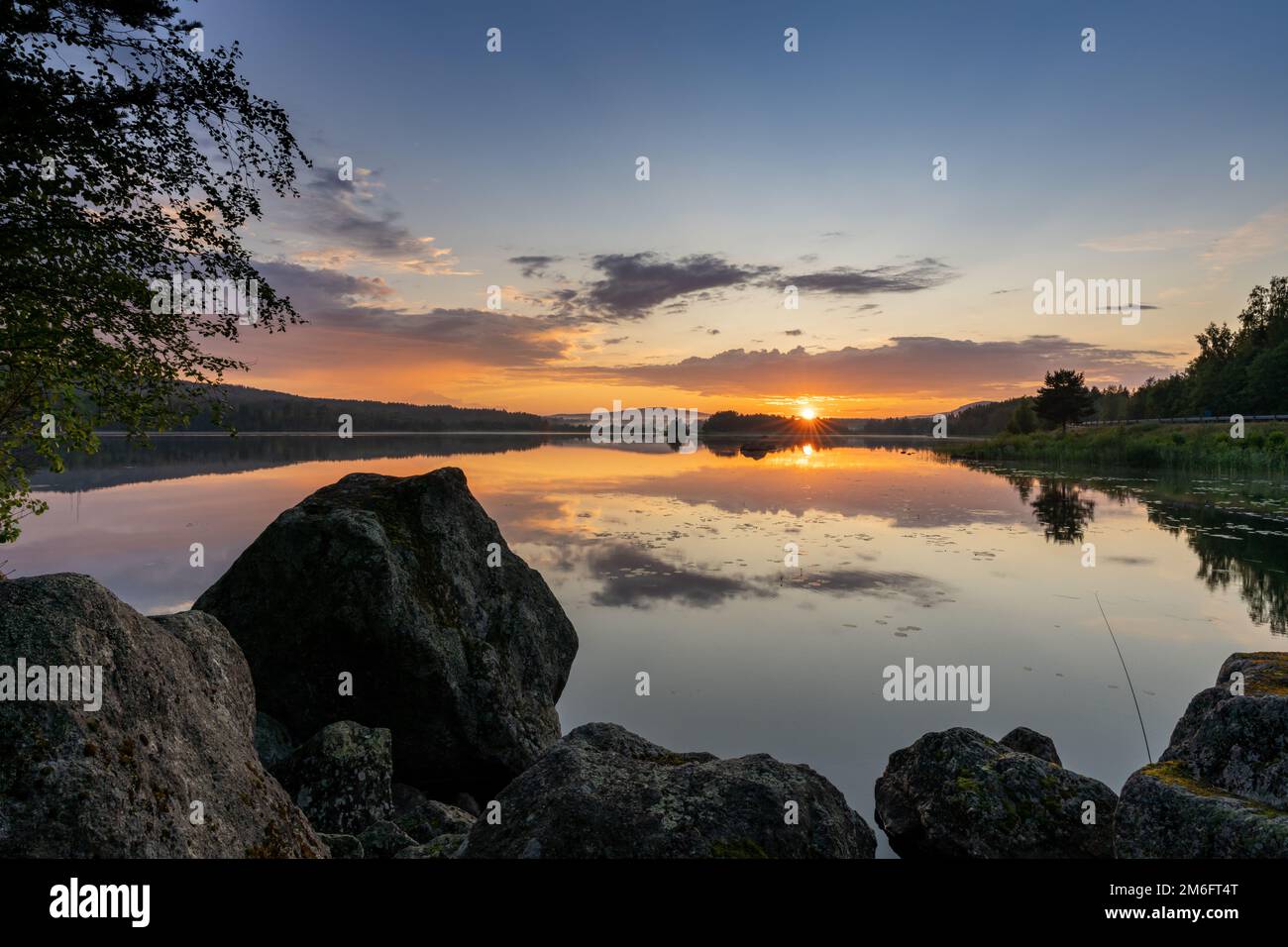Colorful sunset over a calm lake with reflections in the water and ...
