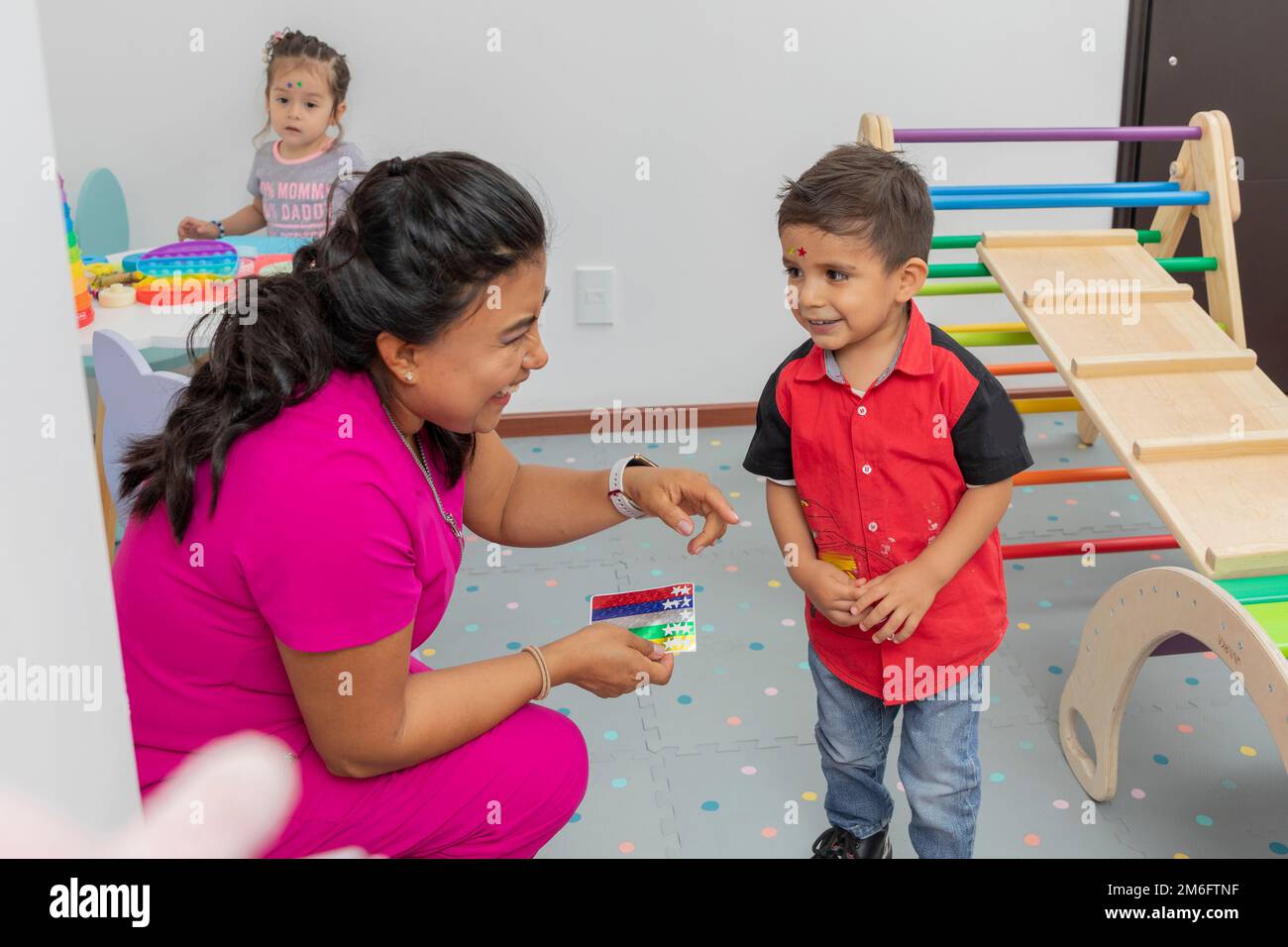 Pediatric doctor laughing with a child, in the play area of her medical ...