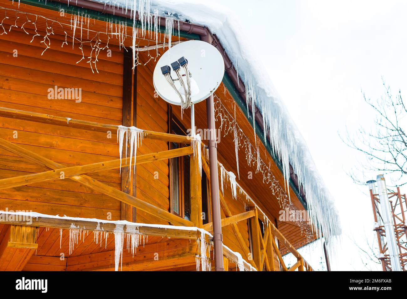Satellite antenna dish covered with snow hanging on a front cottage ...