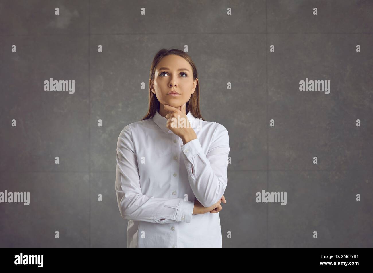 Young caucasian woman thinking and touching chin looking up stand over ...