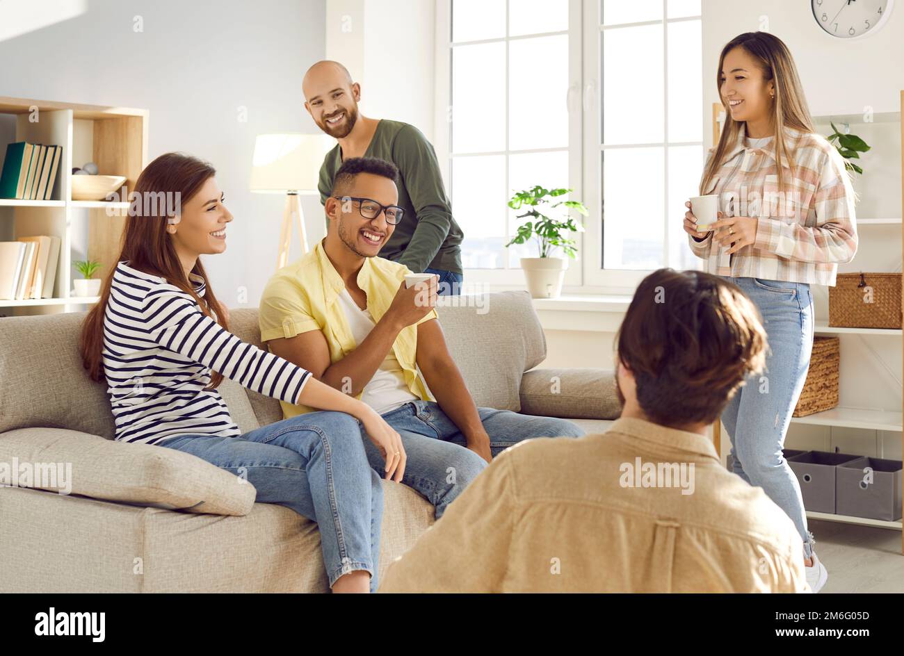Diverse group of happy young people talking and having fun at friendly ...